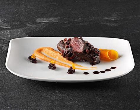 A White Plate Topped With Food On Top Of A Black Counter Next To An