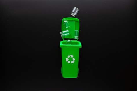 유리 쓰레기를 재활용합니다 재활용 유리를 위한 녹색 쓰레기통은 검은 색 배경에 쓰레기를 수 있습니다 쓰레기 쓰레기를 폐기하고 환경을 절약하기 위해 용기를 보관하십시오 공간을