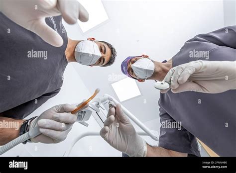 Par Le Dessous De Dentiste Mâle Avec Miroir Et Sonde Et Assistant Avec