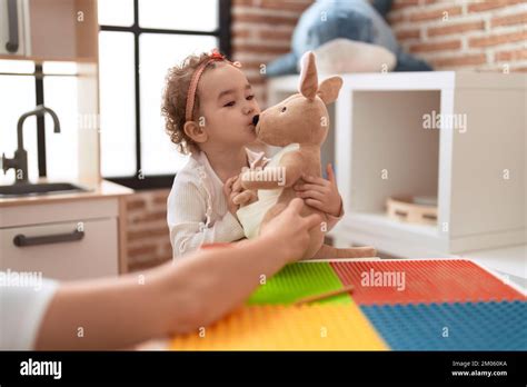 Adorable Caucasian Girl Kissing Kangaroo Toy Standing At Kindergarten