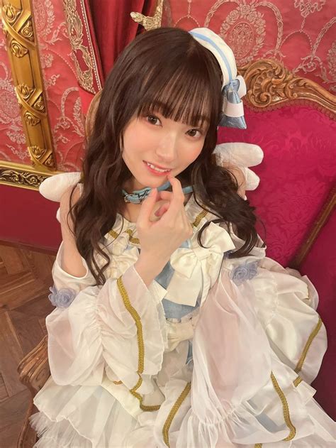 A Woman In A White Dress Is Sitting On A Red Chair And Posing For The