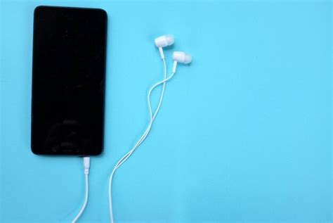 Premium Photo Smartphone Plugged In With White Headphones On A Blue