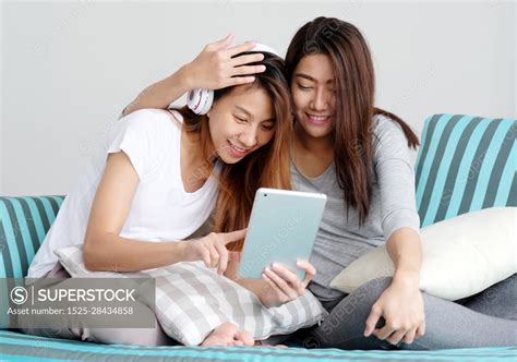 Lgbt Young Cute Asian Lesbian Couple Wearing Headphone And Using