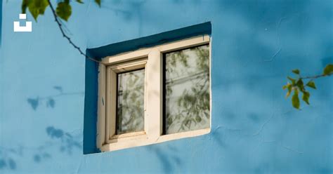 창문과 그 앞에 나무가 있는 파란색 건물 사진 Unsplash의 무료 파랑 이미지