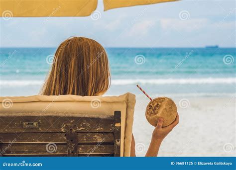 Young Woman Drinking Coconut Milk On Chaise Longue On Beach Stock