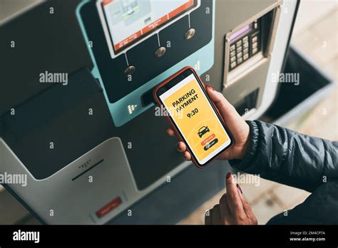 Woman Paying For Parking Ticket At Car Parking Payment Machine Using Mobile App On Smartphone
