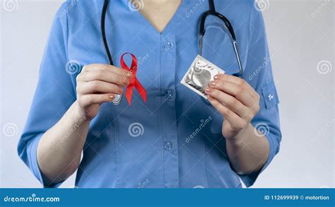 Gynecologist Holding Red Ribbon And Condom Aids Awareness Warning