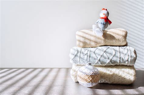 밝은 배경에 나무 테이블에 크리스마스 장식 및 장난감 눈사람으로 따뜻한 니트 스웨터의 더미 아늑한 겨울 복사 공간을 모의 배경