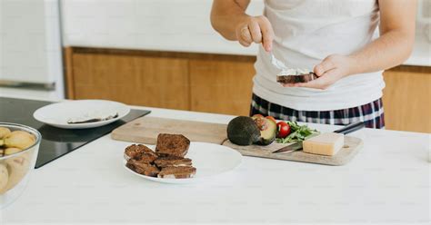 현대적인 흰색 주방에서 아보카도로 건강한 토스트를 만드는 사람 곡물 빵 아보카도 토마토 루꼴라 및 치즈로 만든 샌드위치