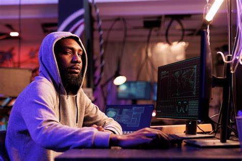 Premium Photo Hacker In Hood Hacking Computer System And Looking At