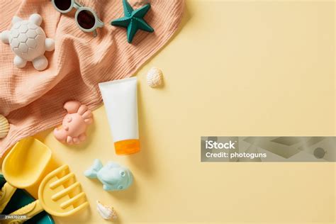 평평하게 놓인 자외선 차단제 로션 튜브 어린이 선글라스 및 모래 몰드가 모래 컬러 테이블에 놓여 있습니다 유아 스킨 케어 자외선