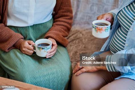 집에서 소파에 그녀의 연로 친척과 커피를 마시는 인식 할 수없는 젊은 여성의 샷 차 뜨거운 음료에 대한 스톡 사진 및 기타