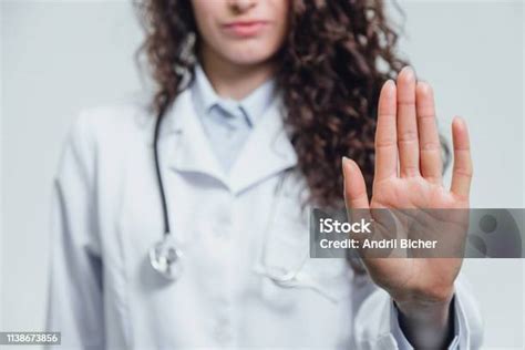 젊은 아름 다운 여자 의사 몸짓 중지 합니다 아마 여성 의사는 회색 배경 위에 제스처 중지를 보여줍니다 거절에 대한 스톡 사진 및 기타 이미지 Istock