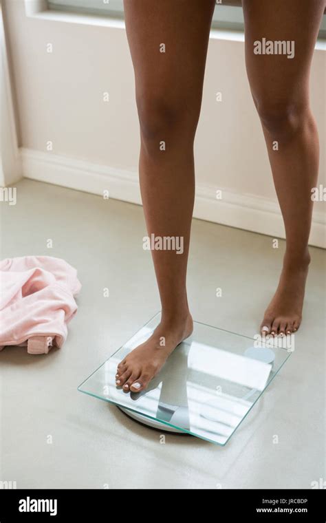 Low Section Of Woman Standing On Weight Scale In Bathroom At Home Stock Photo Alamy