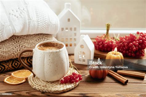 가을 작곡 뜨거운 커피 한 잔 장식용 작은 집 호박 양초 책 나무 테이블에 따뜻한 스웨터 계절에 따라 따뜻한 아침 커피 아늑한