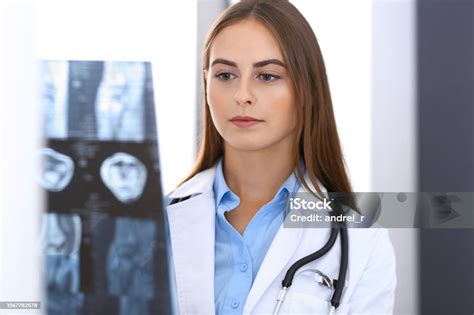 의사 여자 병원에 창문 가까이 서 있는 동안 X 선 사진 검사 외과 의사 또는 직장에서 정형 외과입니다 의학 및 건강 관리