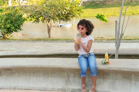 Curly Haired Girl In A Park With A Glass Of Healthy Juice Stock Image