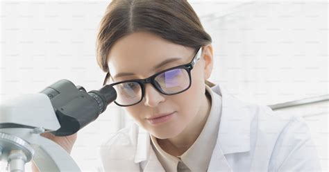 실험실에서 현미경으로 코로나바이러스 특성을 연구하면서 메모를 하는 화이트코트를 입은 갈색 머리 여성 과학 연구원 사진 Unsplash의 과학자 이미지