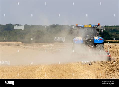 In Parham Rural Suffolk A Harrowing Blue Tractor Making A Drifting Dust