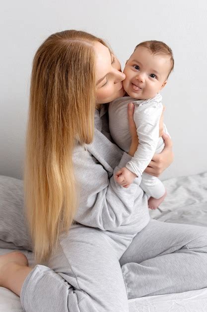Mãe e bebê brincam na cama mãe e filho família feliz linda loira e bebê