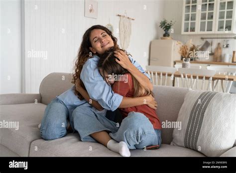 Smiling Supportive Young Mother Hugging Cuddling Teen Daughter Mom