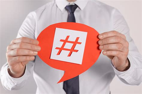 밝은 배경에 해시 태그 기호가있는 종이 연설 거품을 들고있는 남자 클로즈업 Brand Name Online Messaging