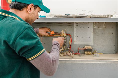전문 전기 남자는 건물의 옥상에 어 컨디셔너의 무거운 단위 고정 이며 녹색 유니폼과 머리 모자를 쓰고 건설업자에 대한 스톡 사진 및 기타 이미지 Istock