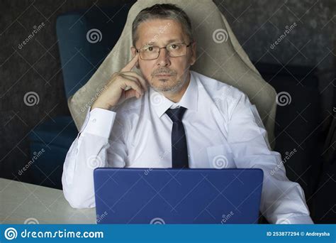 a man in a white shirt is working at home on a laptop remote work