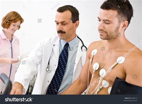 Medical Team Performing An Ekg Test On Young Male Patient Real People