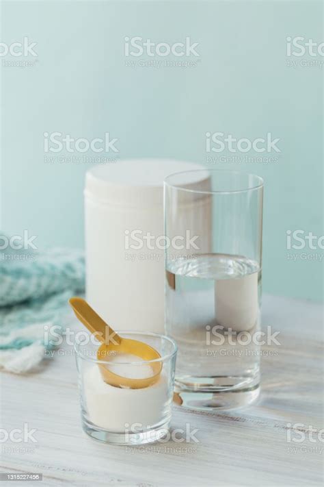 그릇에 콜라겐 분말 물 한 잔과 밝은 파란색 배경에 숟가락을 측정합니다 여분의 단백질 섭취 자연의 아름다움과 건강 보조 개념