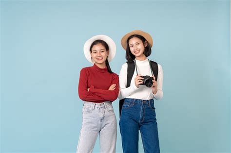 두 명의 동양인 여학생이 조용한 시골을 여행하다가 캐주얼한 복장으로 카메라를 들고 주변의 아름다운 풍경을 기록하고 편집하기 위해 스튜디오에서 사진 촬영을 하러 옵니다 2명에