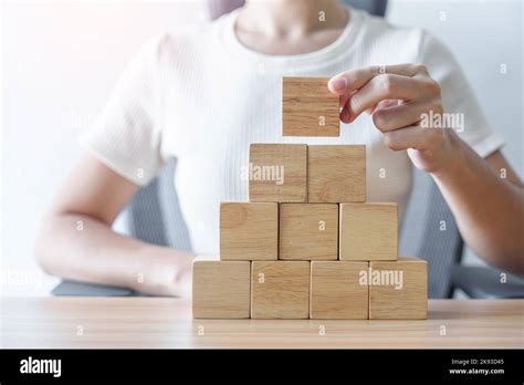 Woman Hand Placing Wood Block On The Building Leadership Business