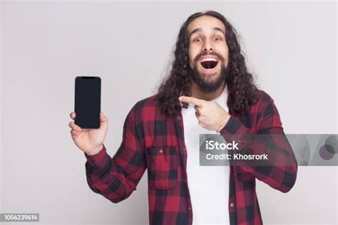 빨간색 체크 무늬 셔츠에 긴 검은 곱슬 머리 서 놀 면 스마트폰 손가락 가리키는 놀된 잘생긴 젊은 사업가 사람들에 대한 스톡 사진 및 기타 이미지 Istock