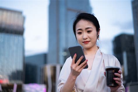 도심 지역에 스마트 폰과 커피 컵을 들고 서있는 아시아 젊은 비즈니스 여성 시내 지역에 대한 스톡 사진 및 기타 이미지 시내