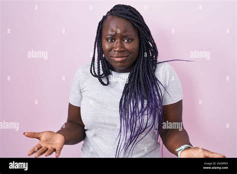 Young African Woman Standing Over Pink Background Clueless And Confused