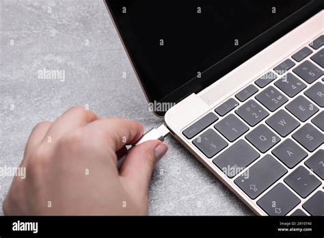 Woman Plugging USB Cable With Type C Connector Into Laptop Port At Grey Table Closeup Stock