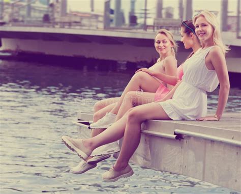 Three Glad Girls Sitting On Pier In Town Stock Image Image Of