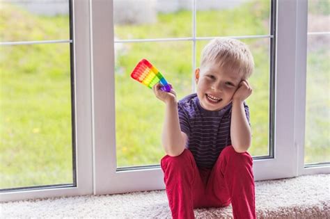 Premium Photo A Small Blonde Boy Sits And Looks At The Camera With A