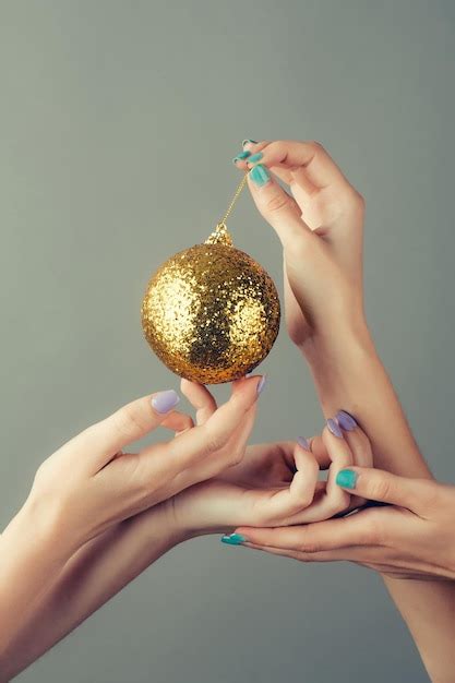 Manos Femeninas Con Bola De Navidad Dorada Foto Premium