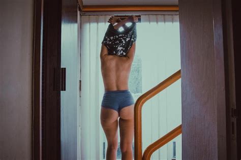 Premium Photo Rear View Of Woman Undressing Near Window