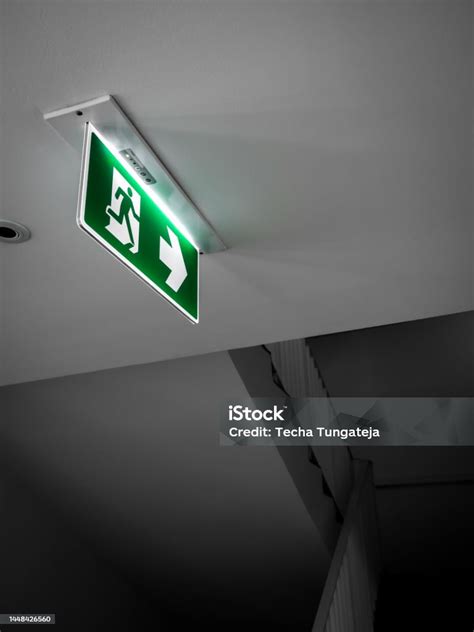 화재 출구 표지판 흰색 천장에 매달린 녹색 비상구 표지판 건물의 계단 화재 탈출문 근처의 어두운 복도에서 빛나는 수직 스타일 구조에 대한 스톡 사진 및 기타 이미지 Istock