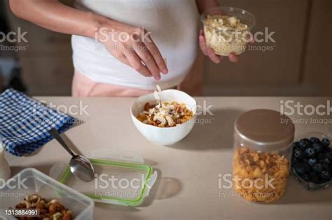 임산부는 아침 식사 콘플레이크 시리얼을 만들고 집에서 부엌에 재료를 추가합니다 섬유질과 영양소로 가득찬 건강한 유기농 식사