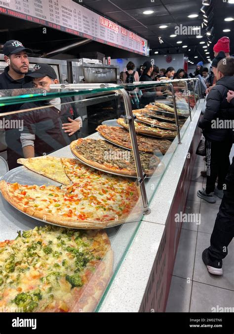Pizzas With A Variety Of Toppings At A Busy Midtown Pizza Parlor In
