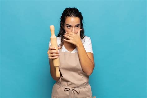 Молодая кавказская женщина закрывает рот руками с шокированным ...