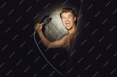 Man Looks Funny Holding Shower Over Him In Black Bathroom Premium Photo