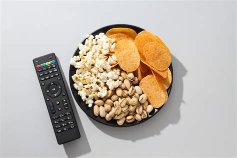 Premium Photo Chips And Popcorn In A Bowl With A Remote Control