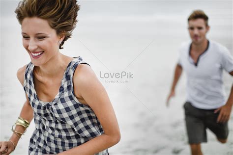 A Couple Chasing Each Other On The Beach Picture And Hd Photos Free