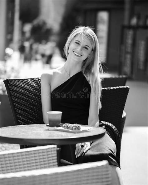 Girl Posing At A Table In A Cafe In The City In A Black Dress Stock