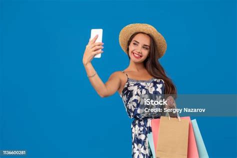 젊은 세련 된 여자 포즈와 파란색 배경에 쇼핑백과 휴대 전화에 Selfie을 복용 가방에 대한 스톡 사진 및 기타 이미지 가방 걷기 고객 Istock