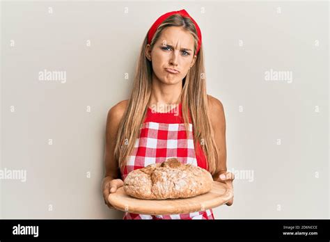 Young Blonde Woman Wearing Baker Uniform Holding Homemade Bread